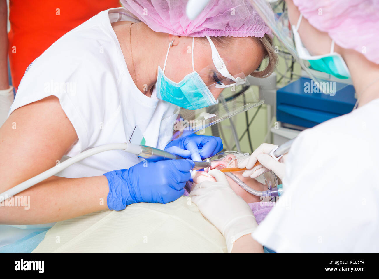 A young woman dentist in white medical uniform and her assistant are ...