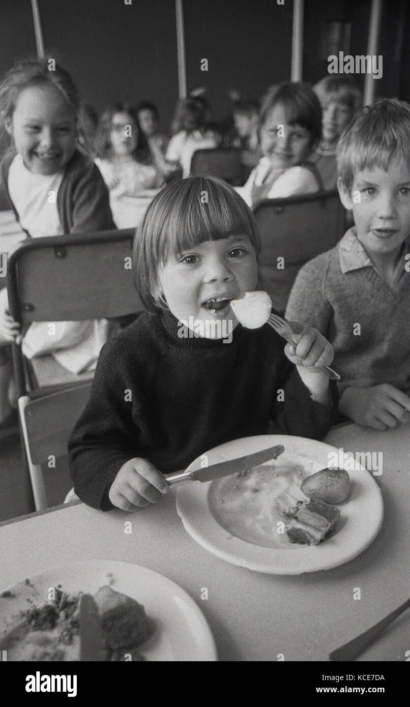 1970s, historical, picture shows a young girl eating her school dinner ...
