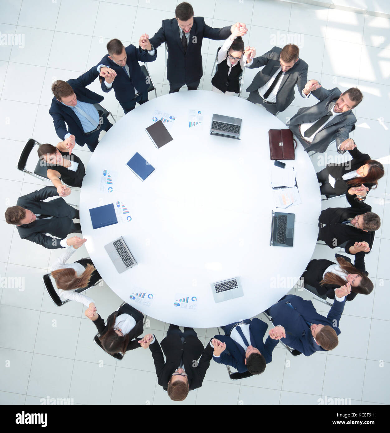large business team sitting at the round table and raising his hands up ...