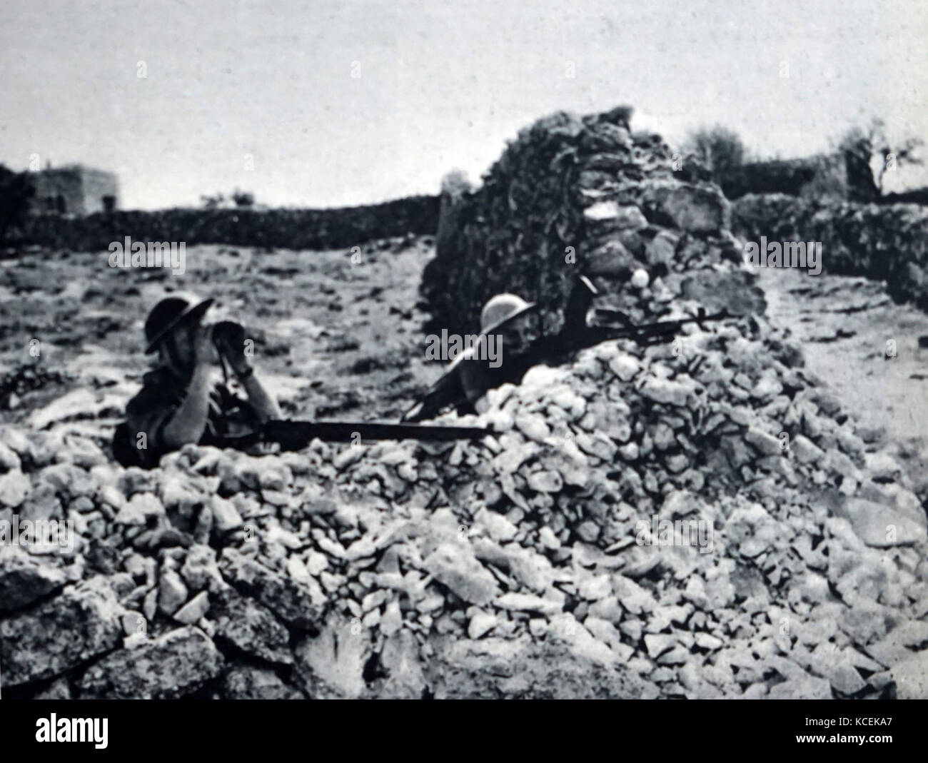 Photograph of British soldiers taking cover behind a destroyed wall ...