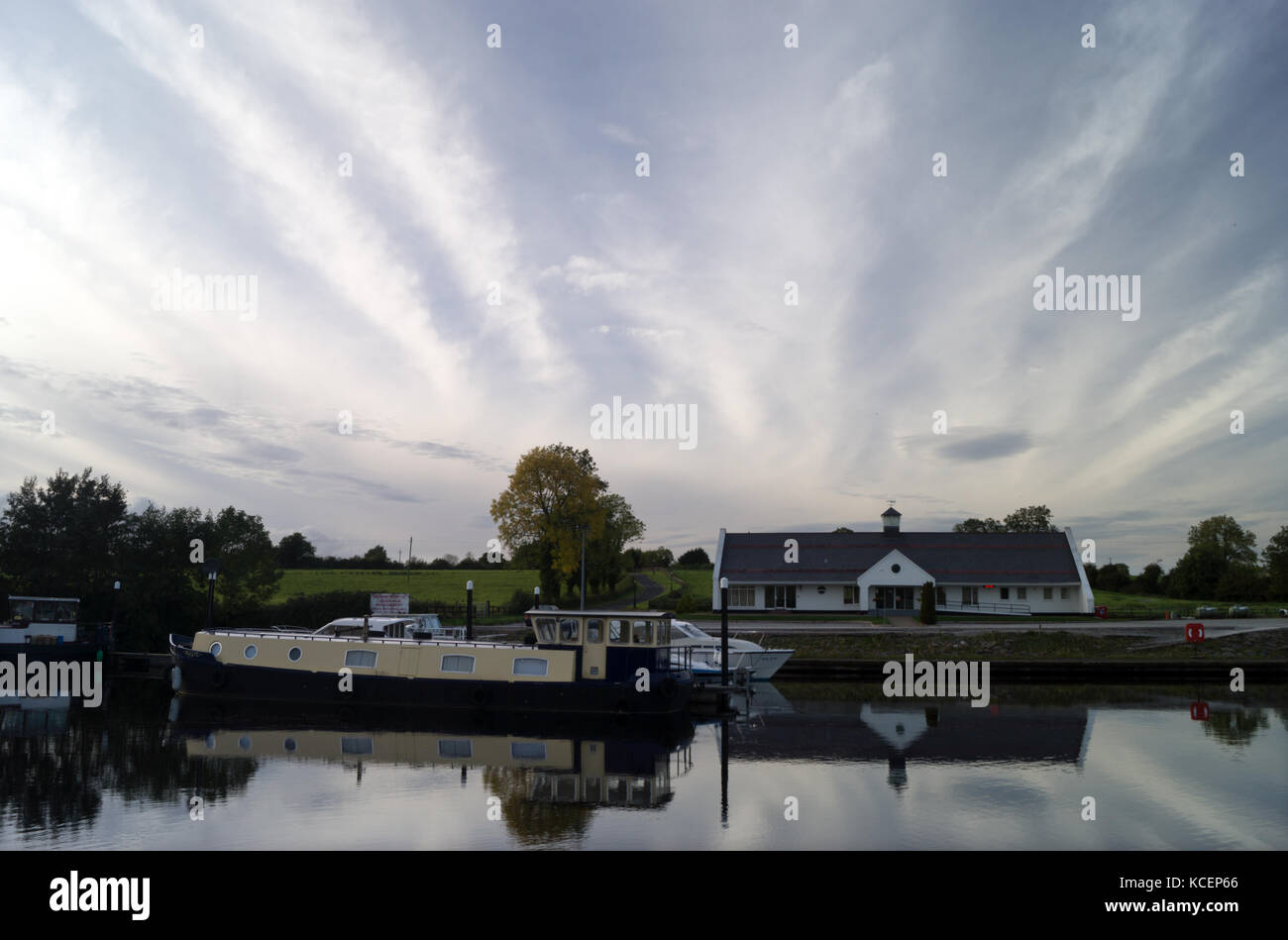 Tranquil marina viewed across river with boats and fan of marestail ...