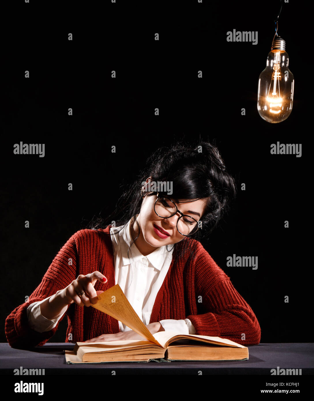 Pretty young woman reading under the light bulb Stock Photo - Alamy
