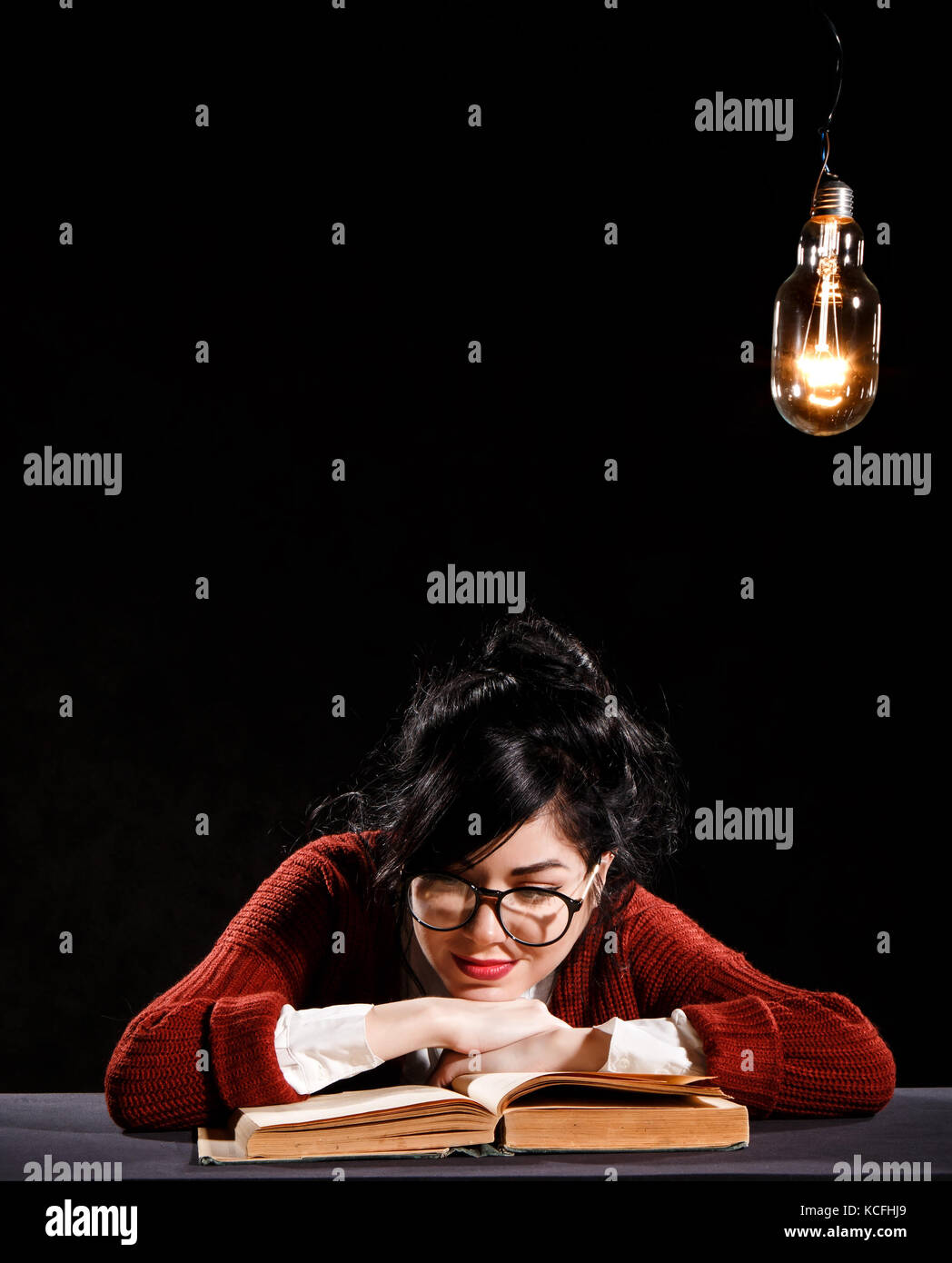 Pretty young woman reading under the light bulb Stock Photo - Alamy