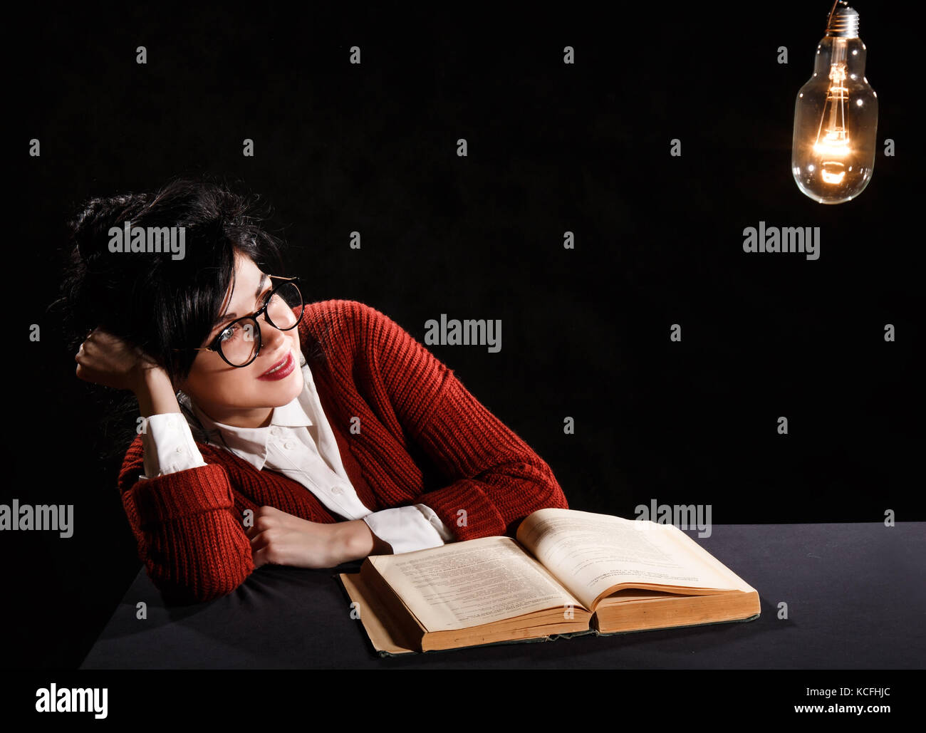 Pretty young woman reading under the light bulb Stock Photo - Alamy