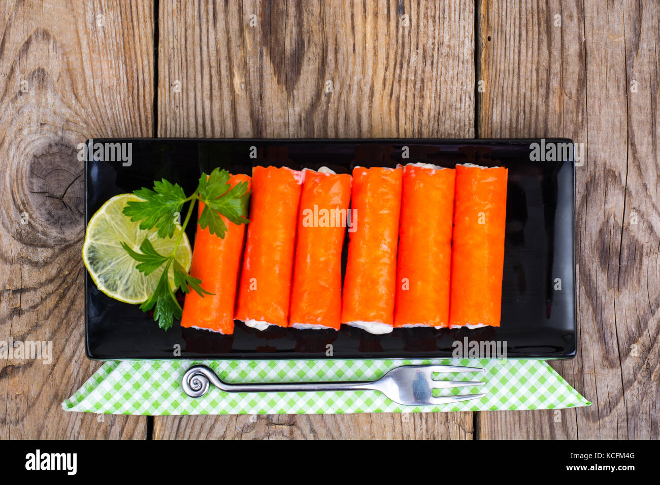 Surimi-crab sticks on black plate Stock Photo - Alamy