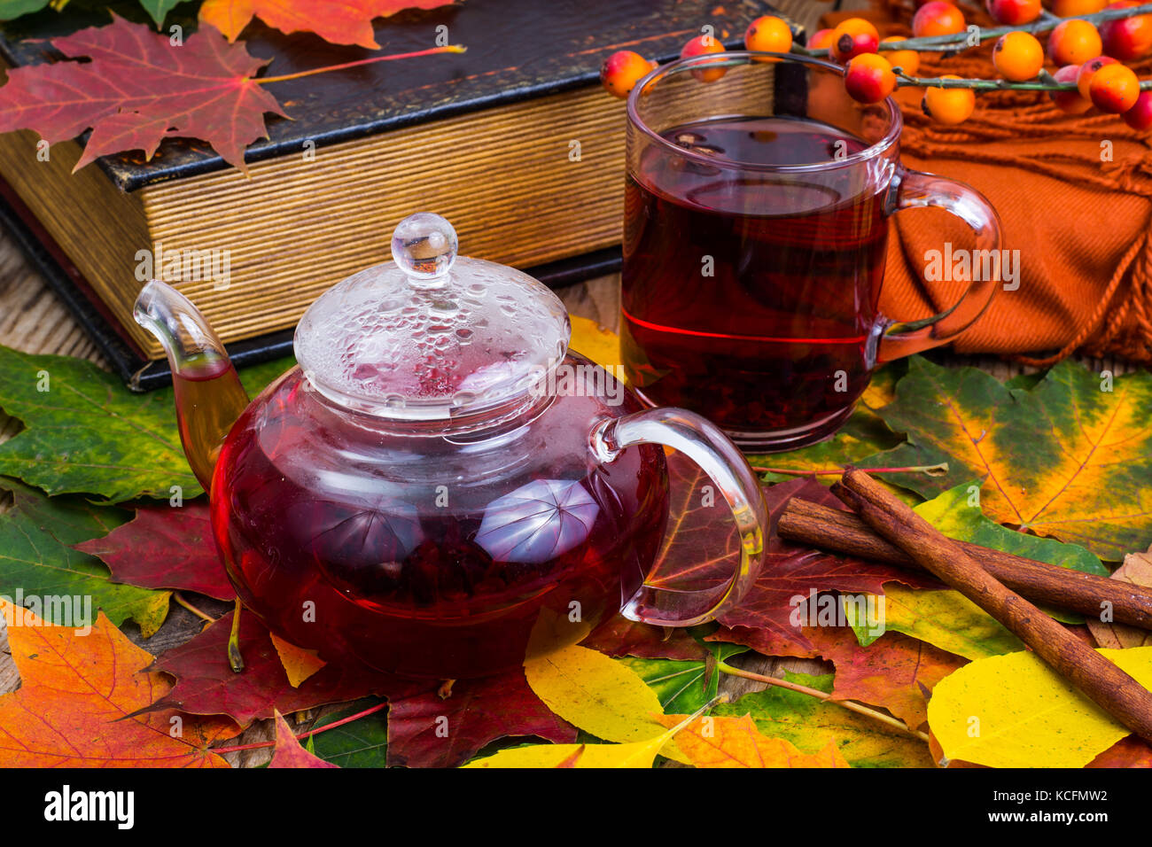 Aromatic red tea, book, colorful autumn leaves on wooden table Stock ...