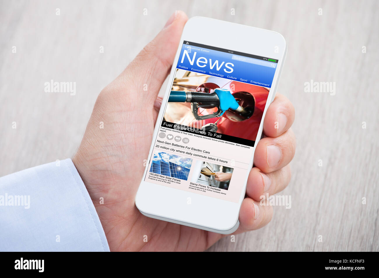Close-up Of Person Hands With Mobile Phone Showing News Over Wooden ...