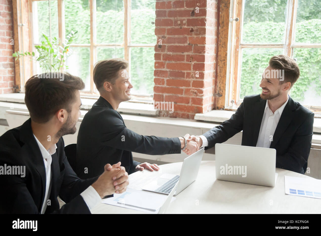 Smiling colleagues greet each other with handshakes. Corporate ...