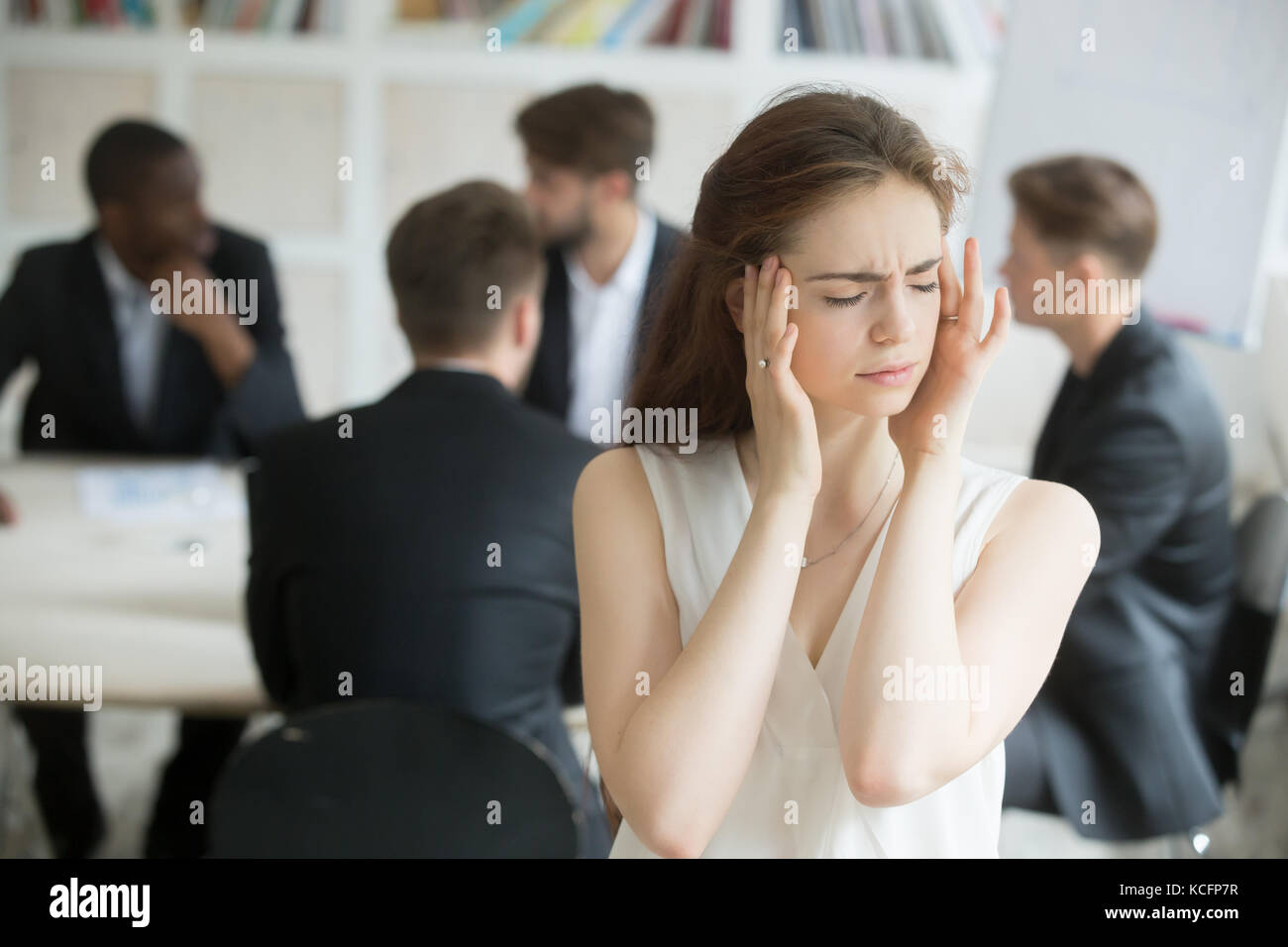 Stressed young female corporate employee having migraine at unproductive briefing. Business ...
