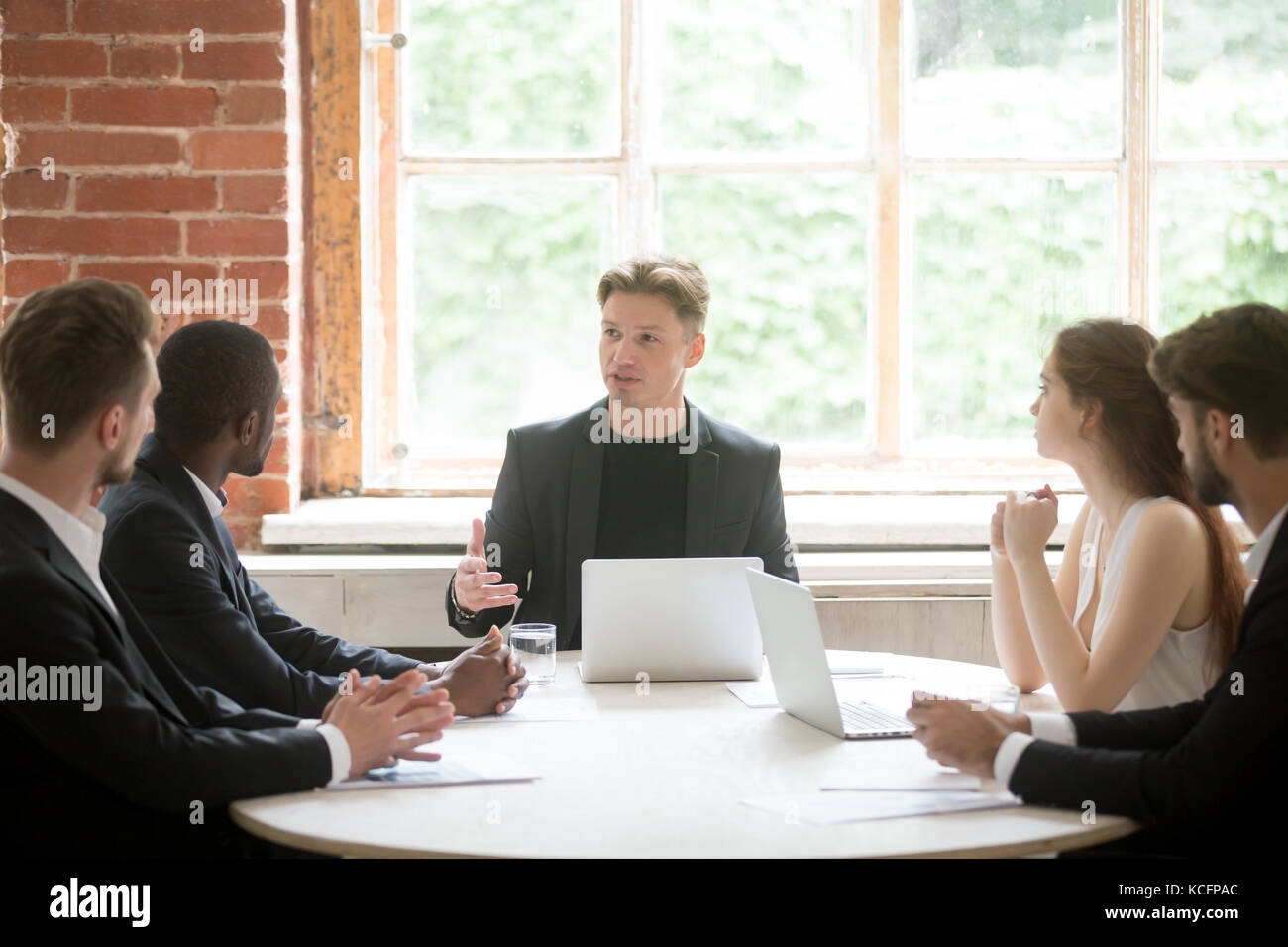 Young serious boss consulting group of employees during briefing ...
