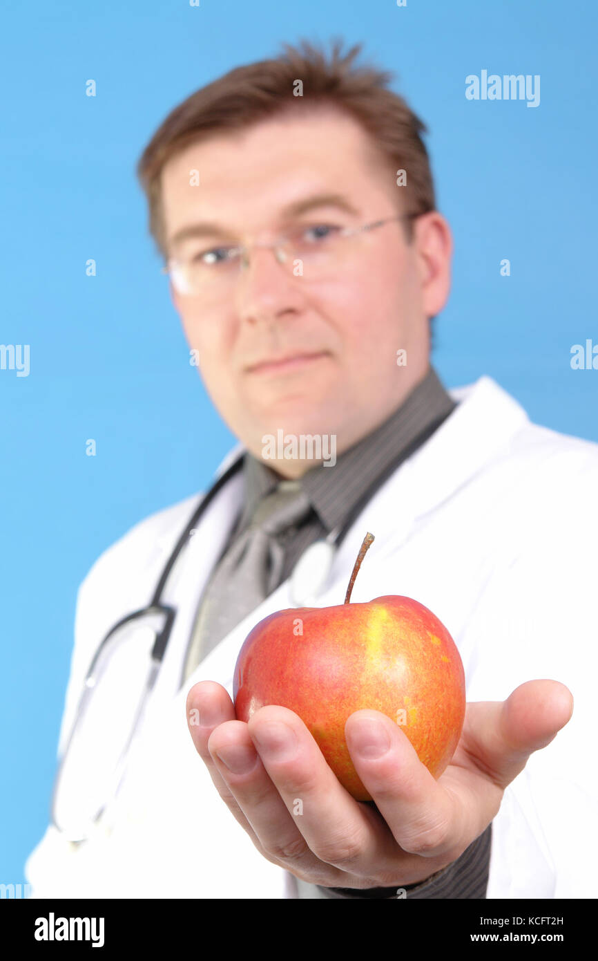 Doctor offering red apple holding in his hand Stock Photo - Alamy