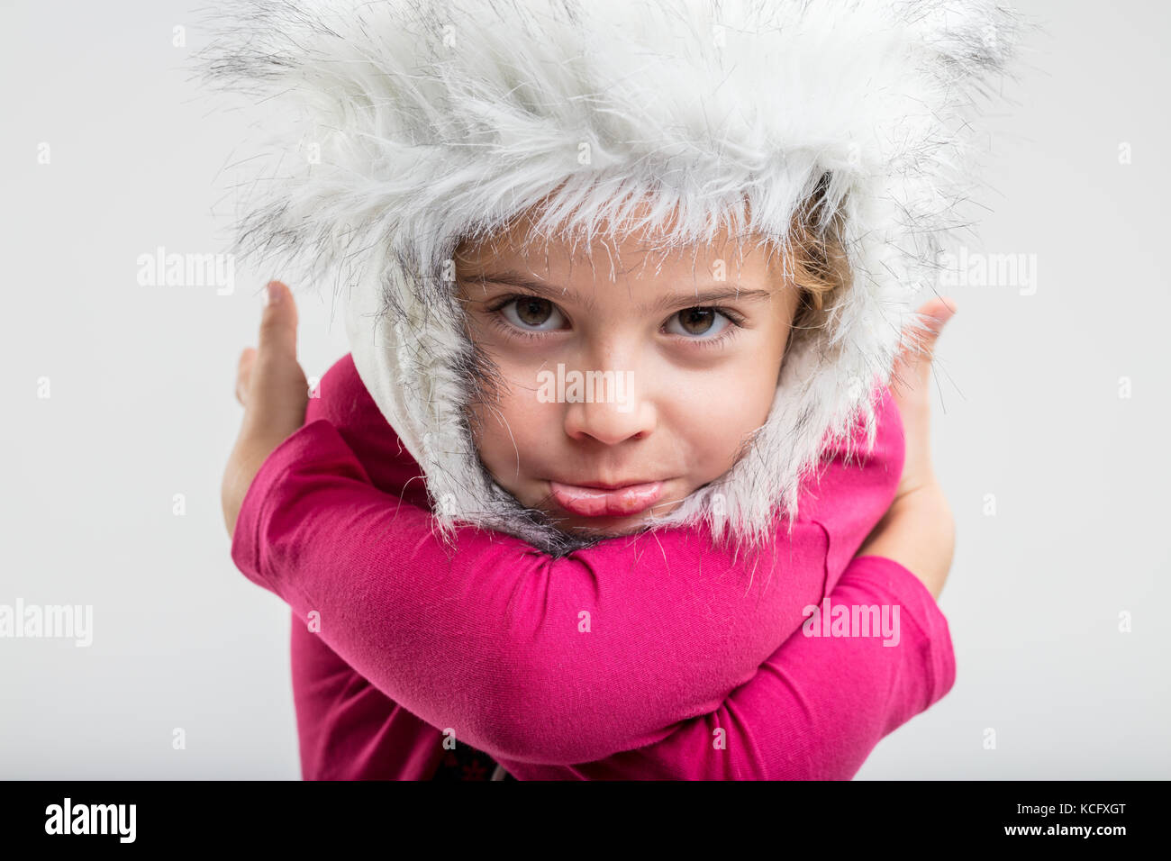 Portrait of preteen girl wearing fluffy winter cap sulking face ...
