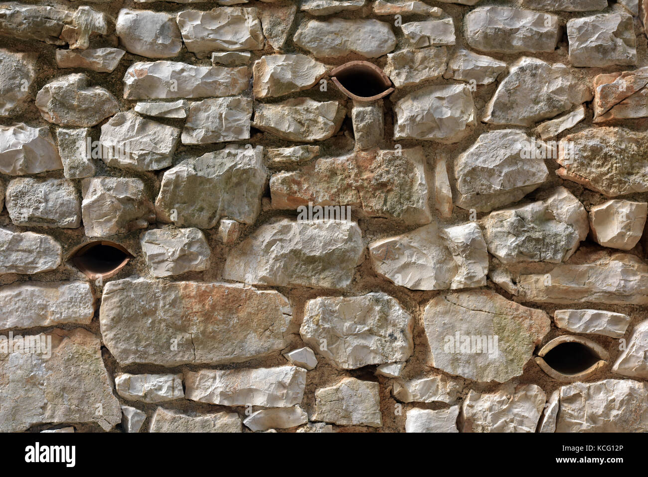 three drainage pipes in a stone wall in the shape of mouths or lips ...