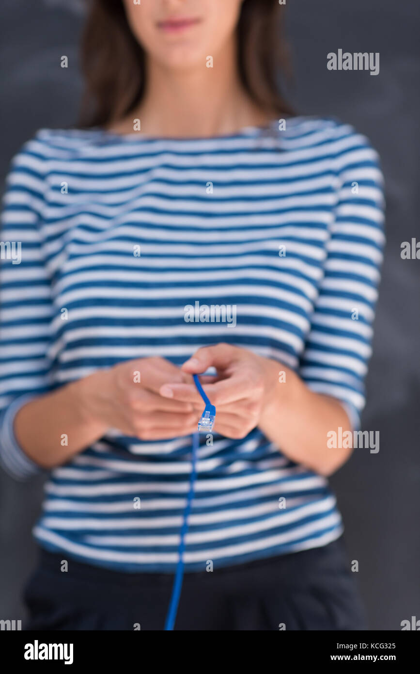 portrait of a young woman holding a internet cable in front of chalk ...