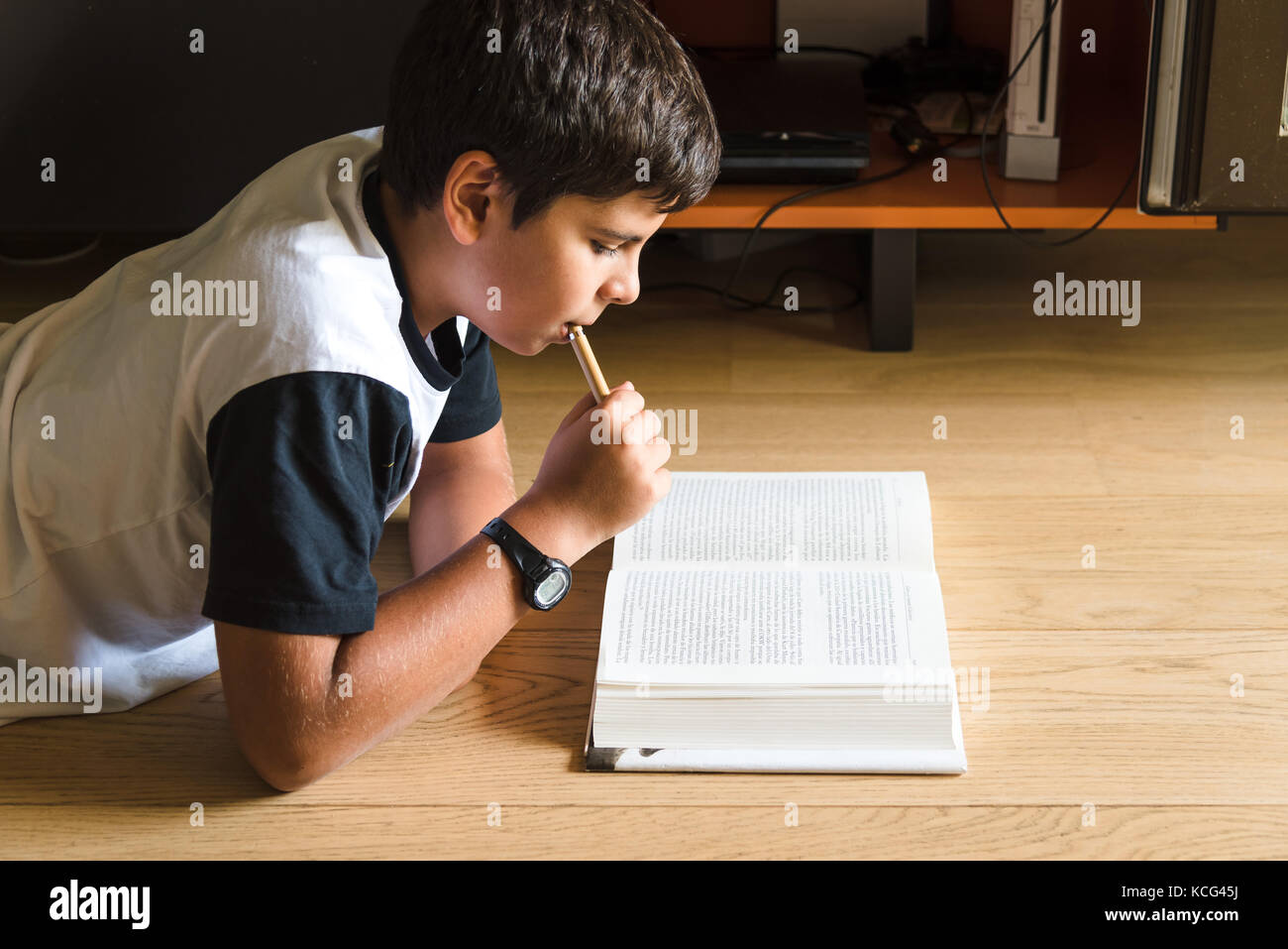 Little boy child reading a book. He lies on the floor Stock Photo - Alamy