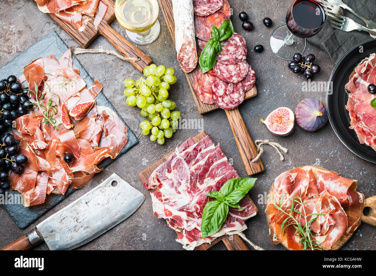 Different types jamon on cutting boardes with figs, grapes and wine ...