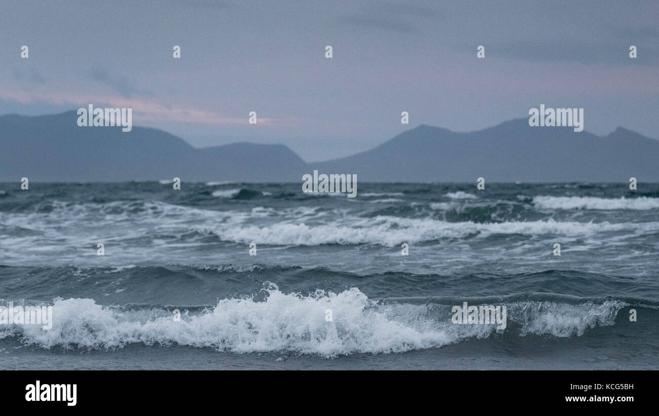 Waves rolling into the beach with the mountains of Snowdonia in the ...