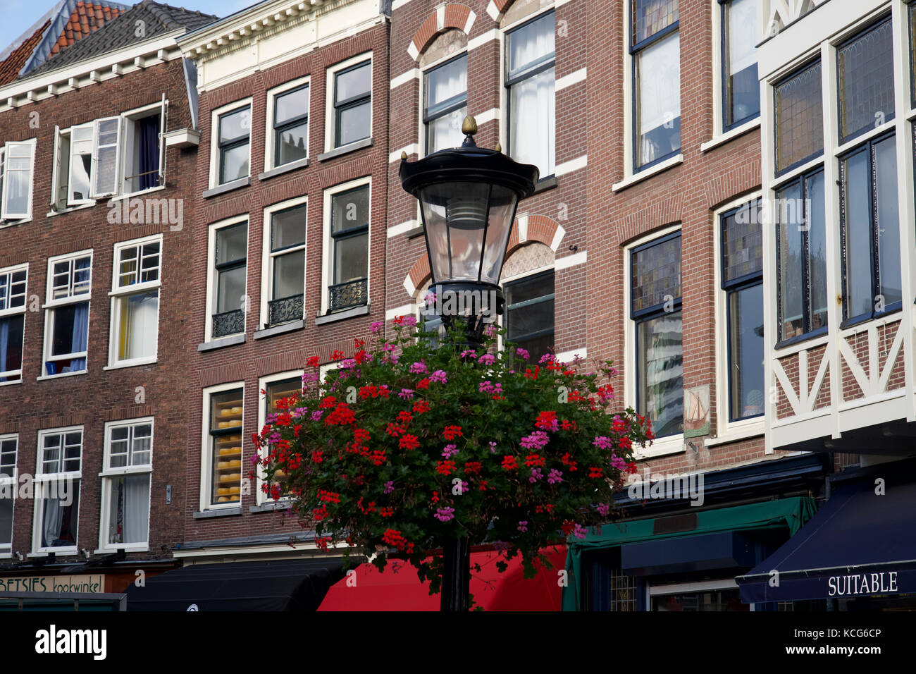 A street lamp with flowers and storage of cheese in a window of a house ...