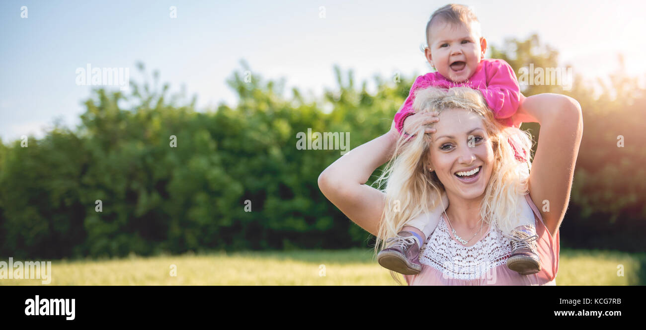 Mother Carrying Baby Daughter Piggyback and standing by the wheat field ...