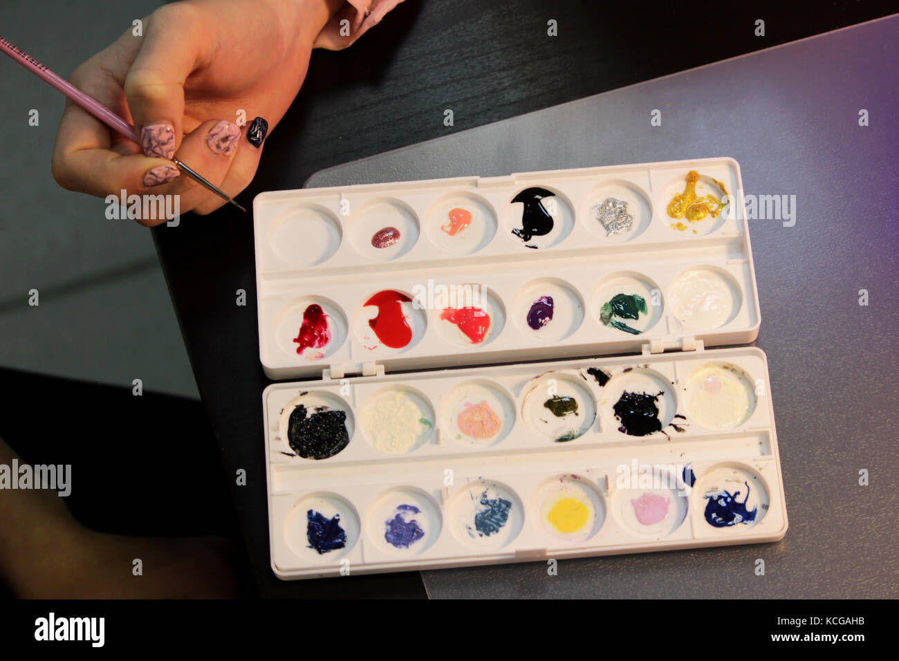 A student at the training courses of manicure applies color gel shell ...