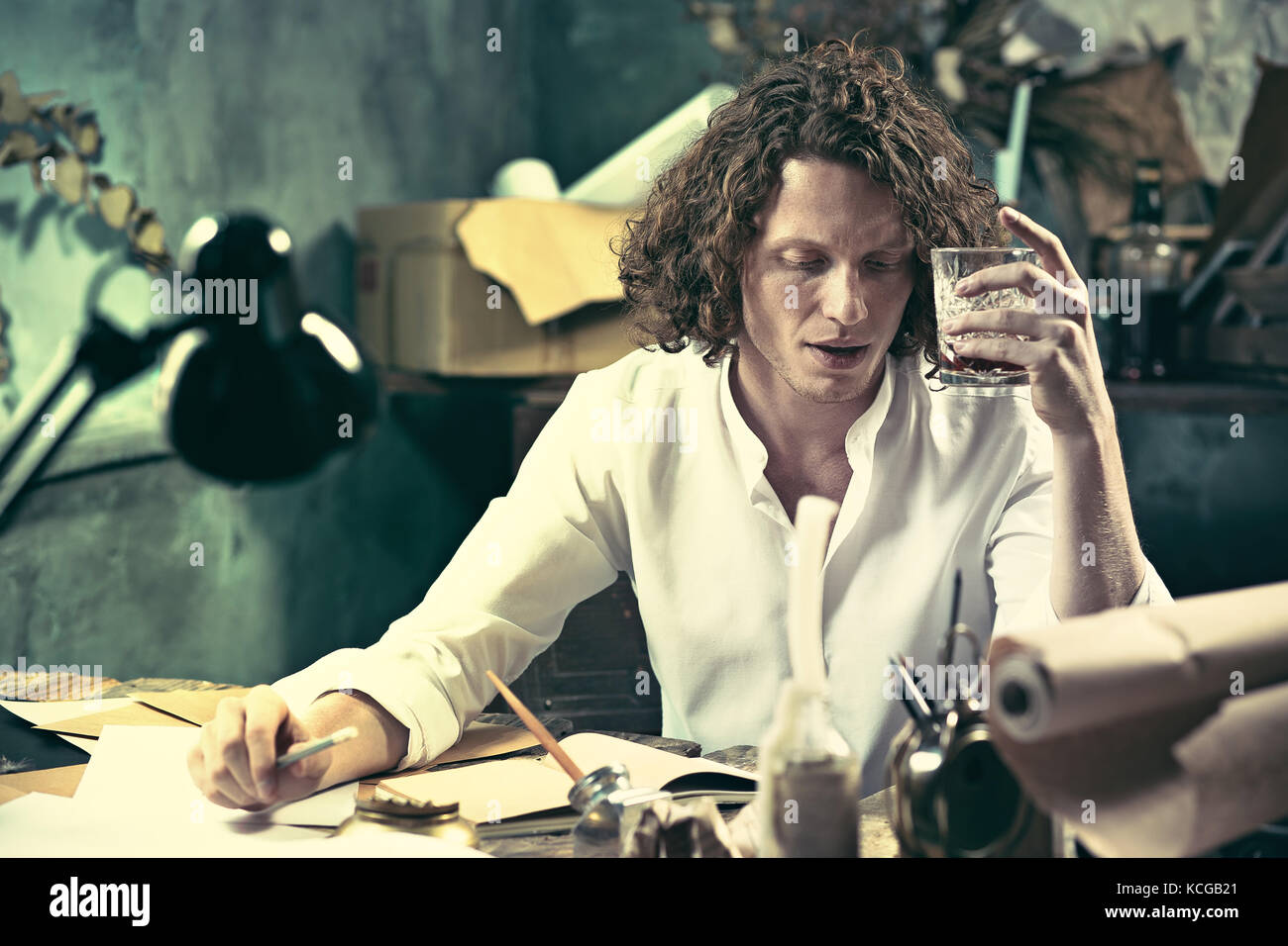 Writer at work. Handsome young writer sitting at the table and writing ...