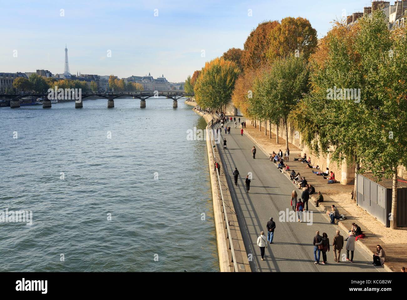 Pedestrians walking along Seine with Eiffel Tower in background in ...