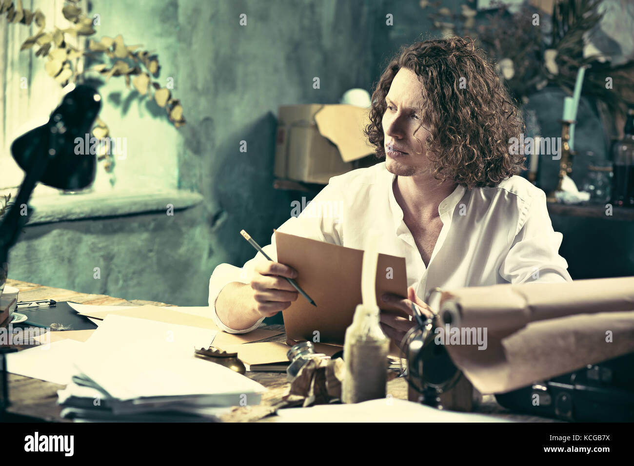 Writer at work. Handsome young writer sitting at the table and writing ...