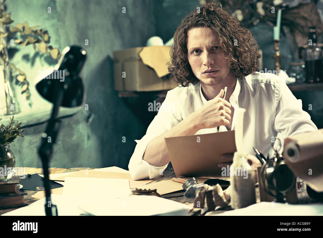 Writer at work. Handsome young writer sitting at the table and writing ...