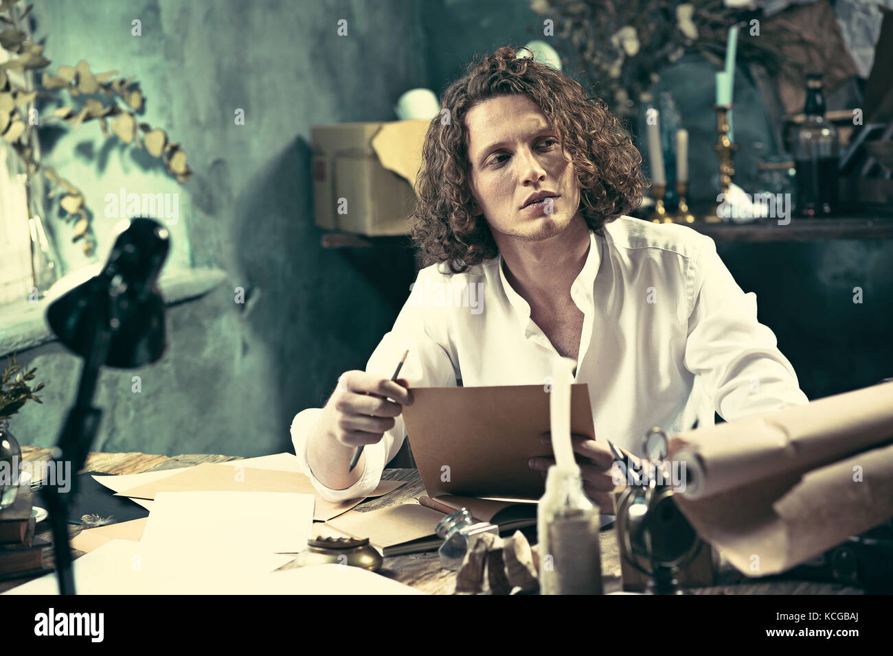 Writer at work. Handsome young writer sitting at the table and writing ...
