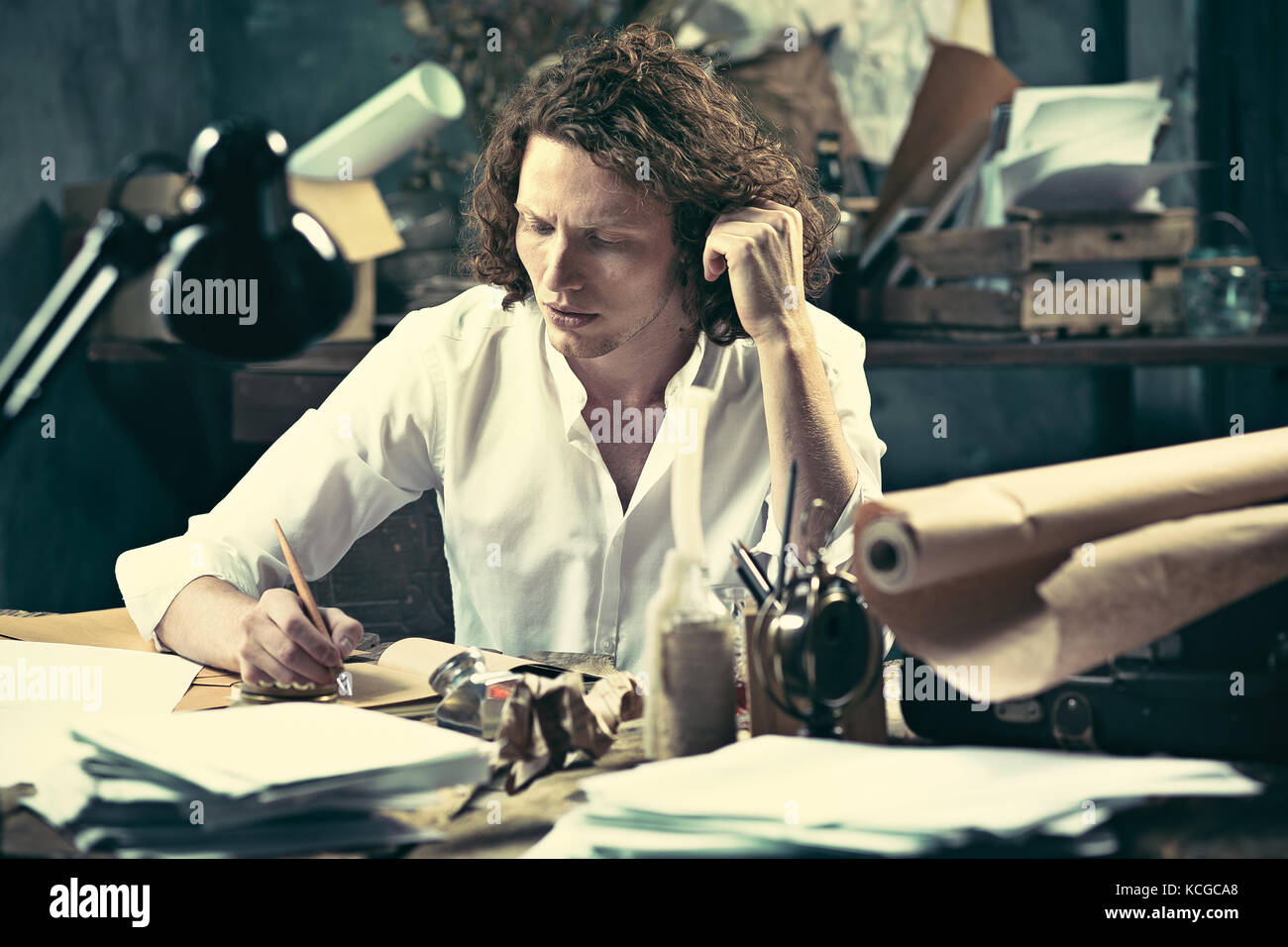 Writer at work. Handsome young writer sitting at the table and writing ...