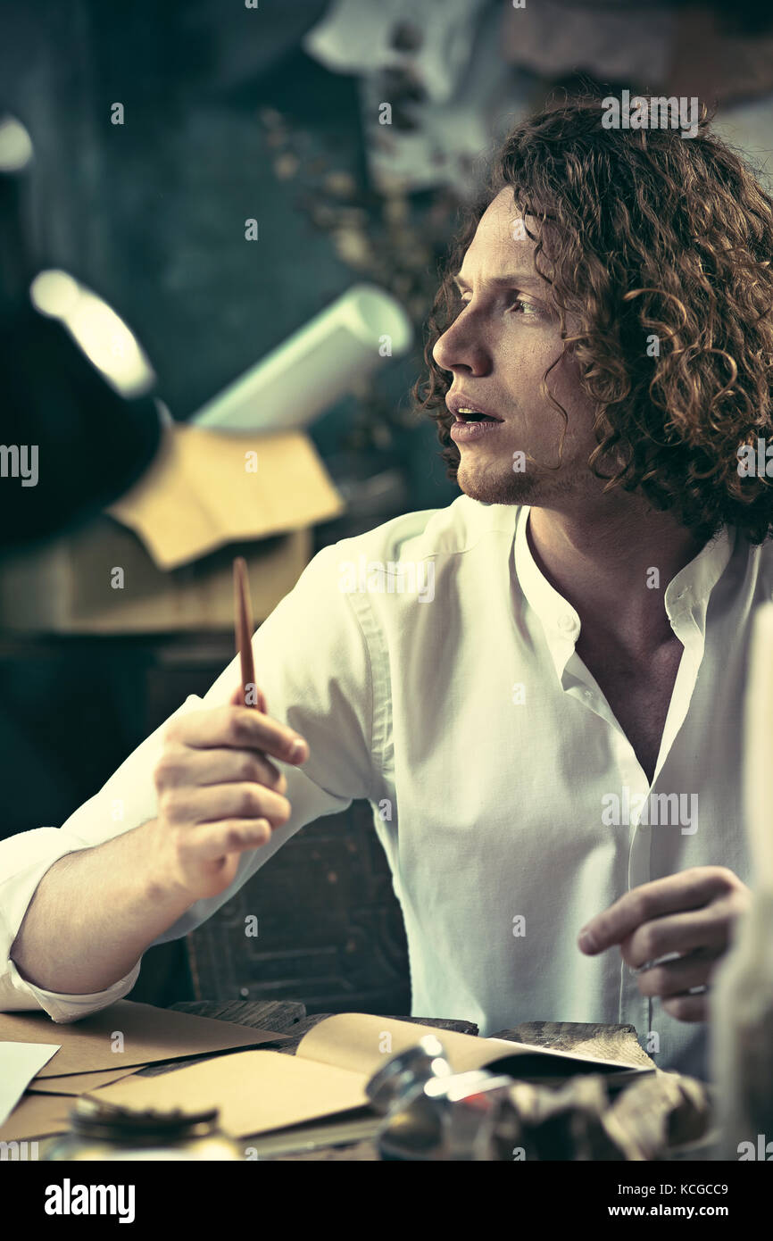 Writer at work. Handsome young writer sitting at the table and writing ...