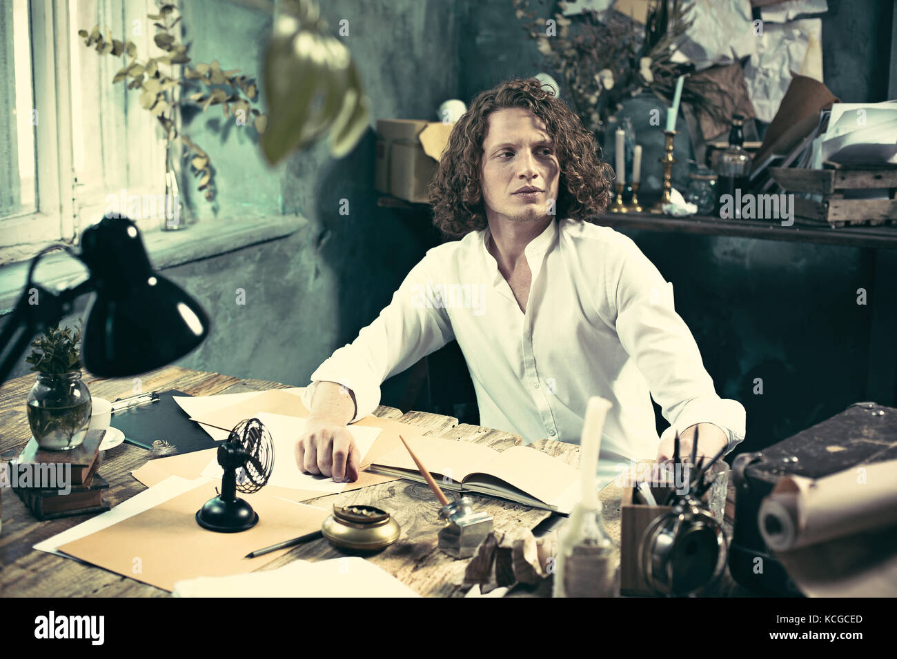 Writer at work. Handsome young writer sitting at the table and writing ...