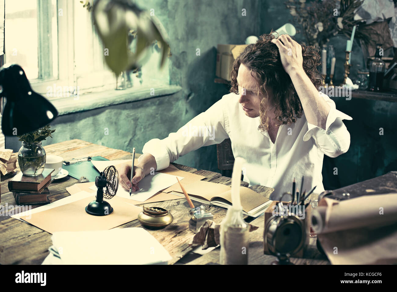 Writer at work. Handsome young writer sitting at the table and writing ...