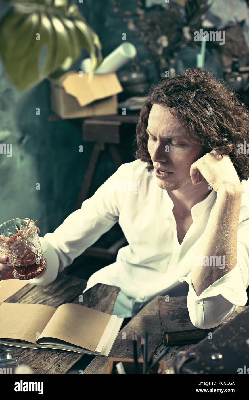 Writer at work. Handsome young writer sitting at the table and writing ...