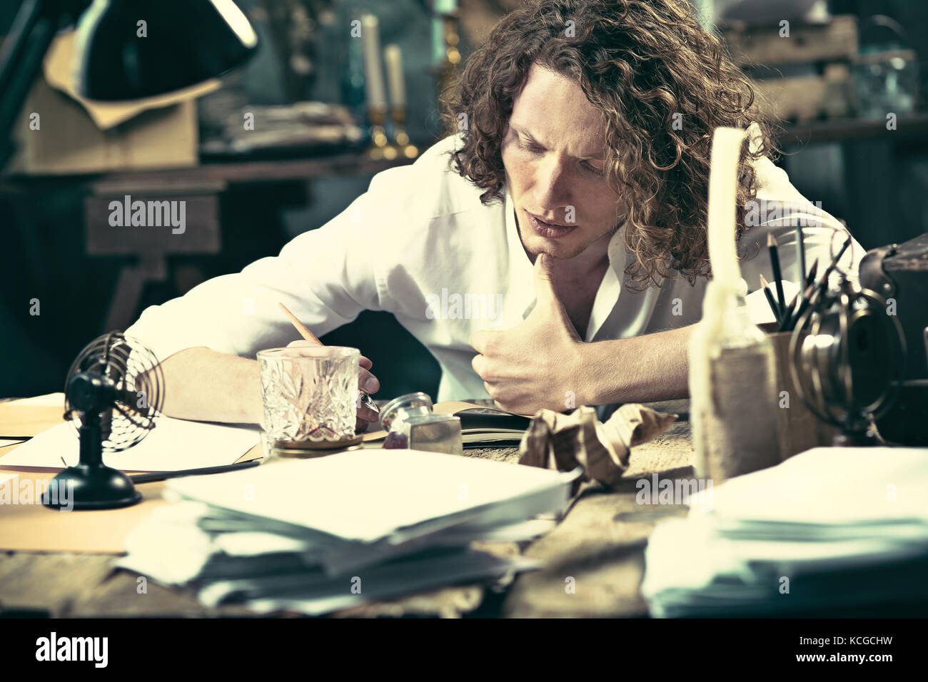 Writer at work. Handsome young writer sitting at the table and writing ...