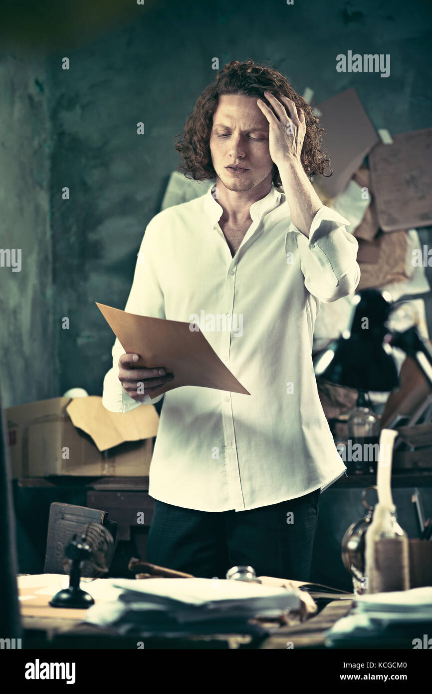 Writer at work. Handsome young writer standing near the table and ...