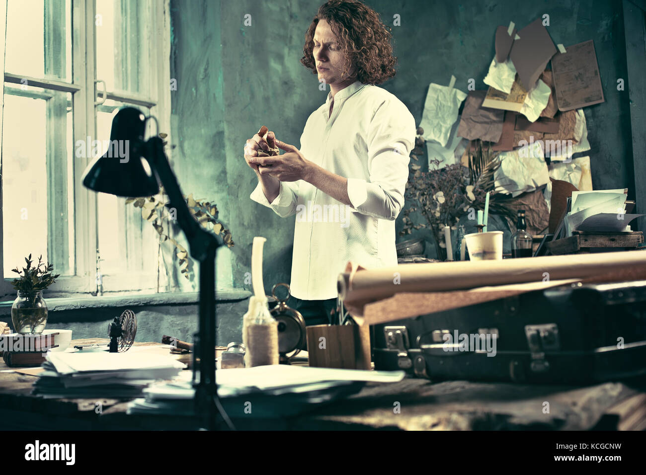 Writer at work. Handsome young writer standing near the table and ...