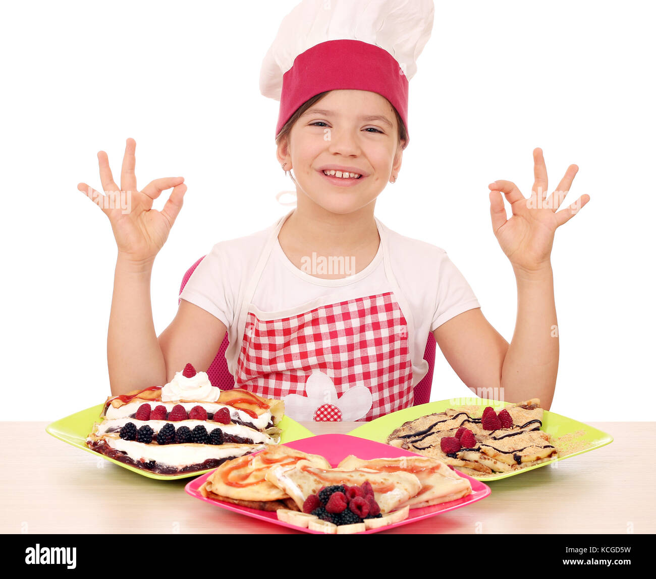 happy little girl cook with delicious crepes on table and ok hand sign ...
