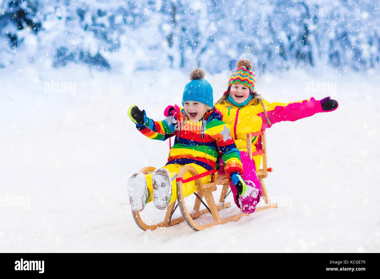 Little girl and boy enjoying sleigh ride. Child sledding. Toddler kid ...