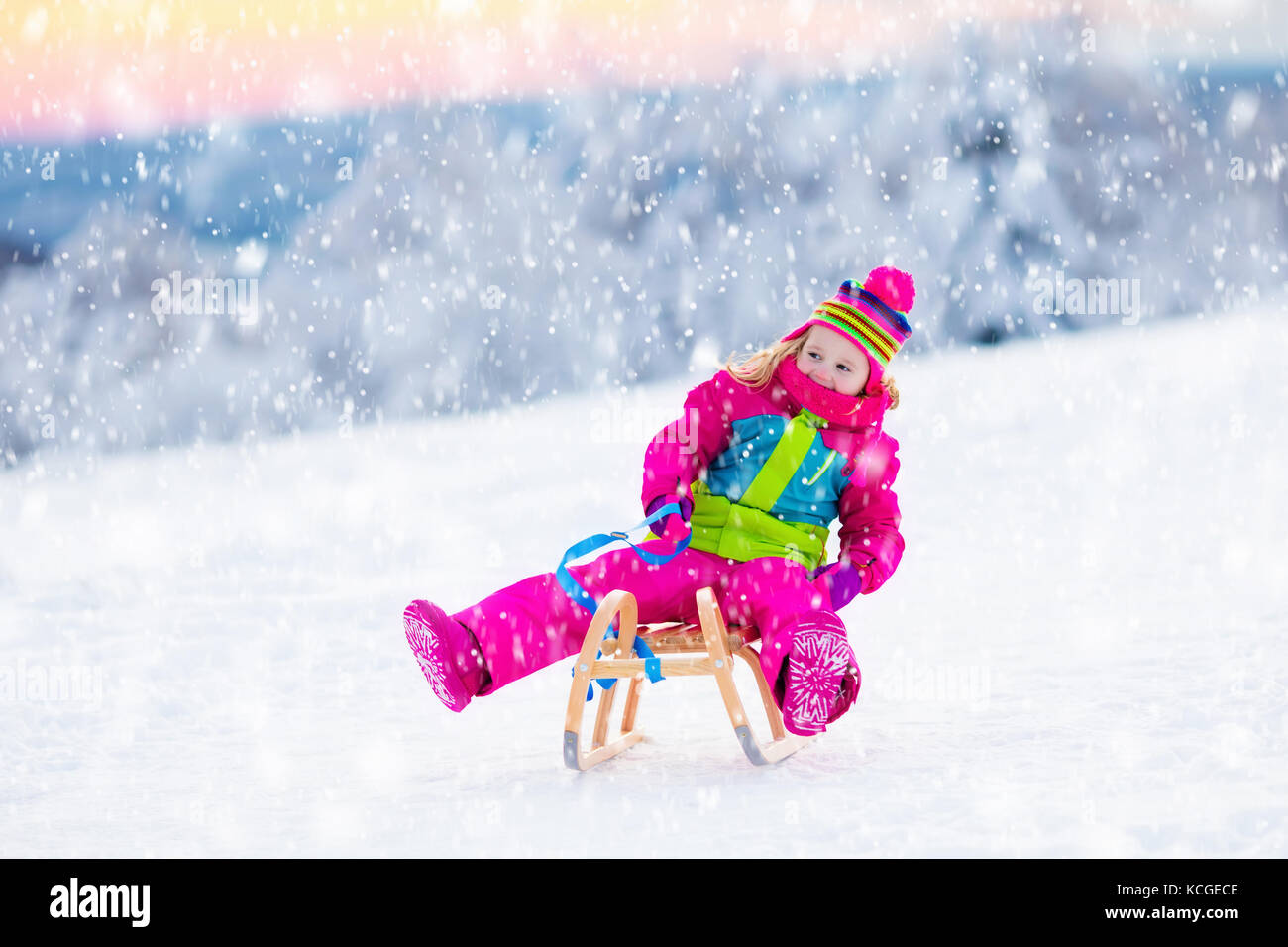 Little girl enjoying a sleigh ride. Child sledding. Toddler kid riding ...