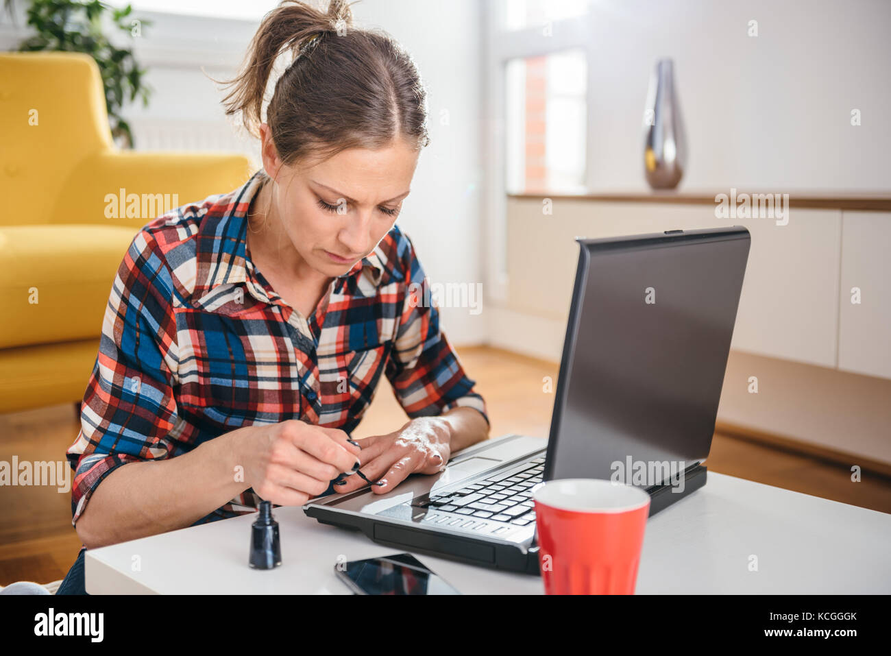 Woman wearing plaid shirt sitting on the floor at the coffee table and ...
