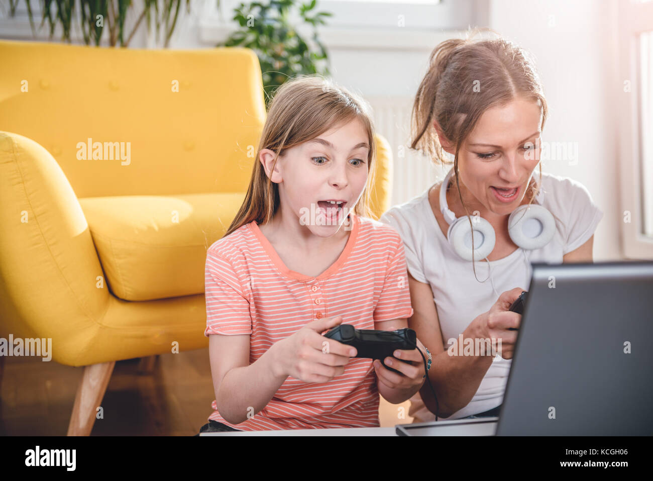 Mother and daughter playing video games on laptop at home Stock Photo ...