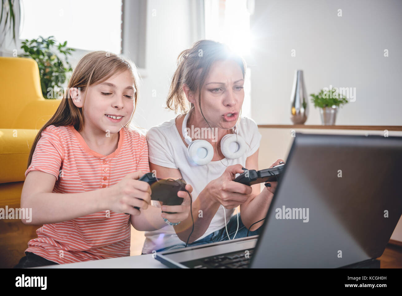 Mother and daughter playing video games on laptop at home Stock Photo ...