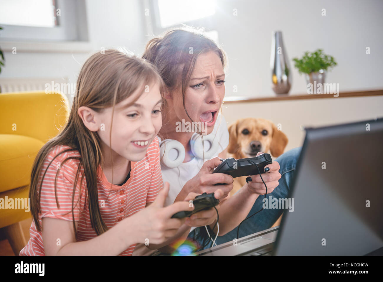 Mother and daughter playing video games on laptop at home Stock Photo ...