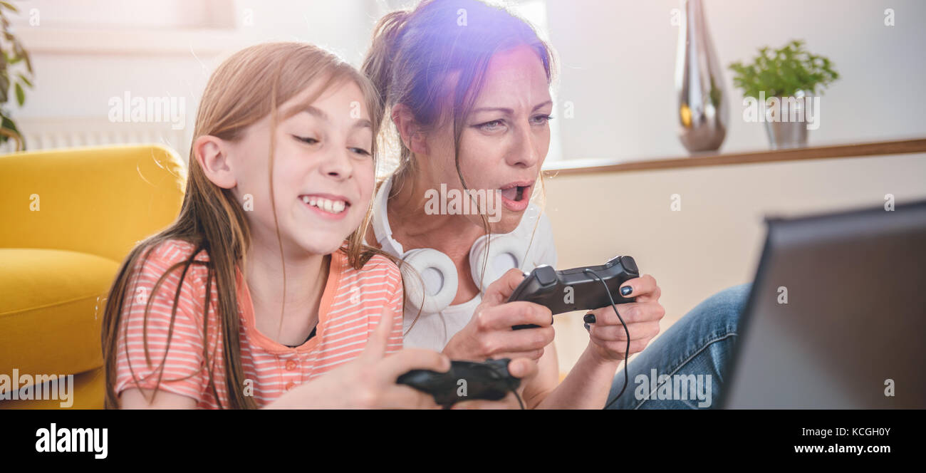 Mother and daughter playing video games on laptop at home Stock Photo ...