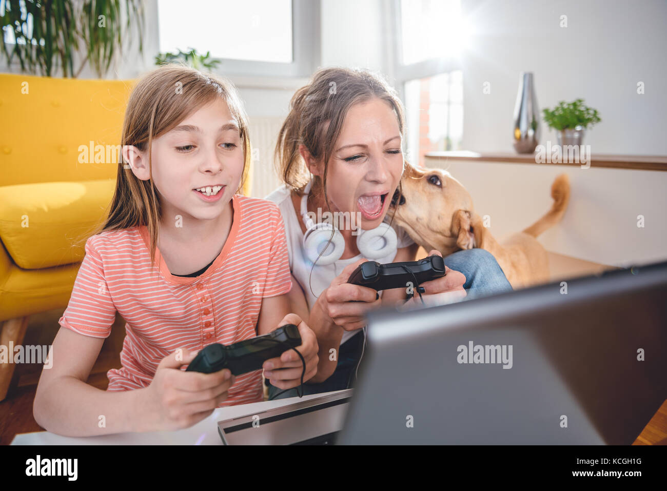 Mother and daughter playing video games on laptop at home Stock Photo ...