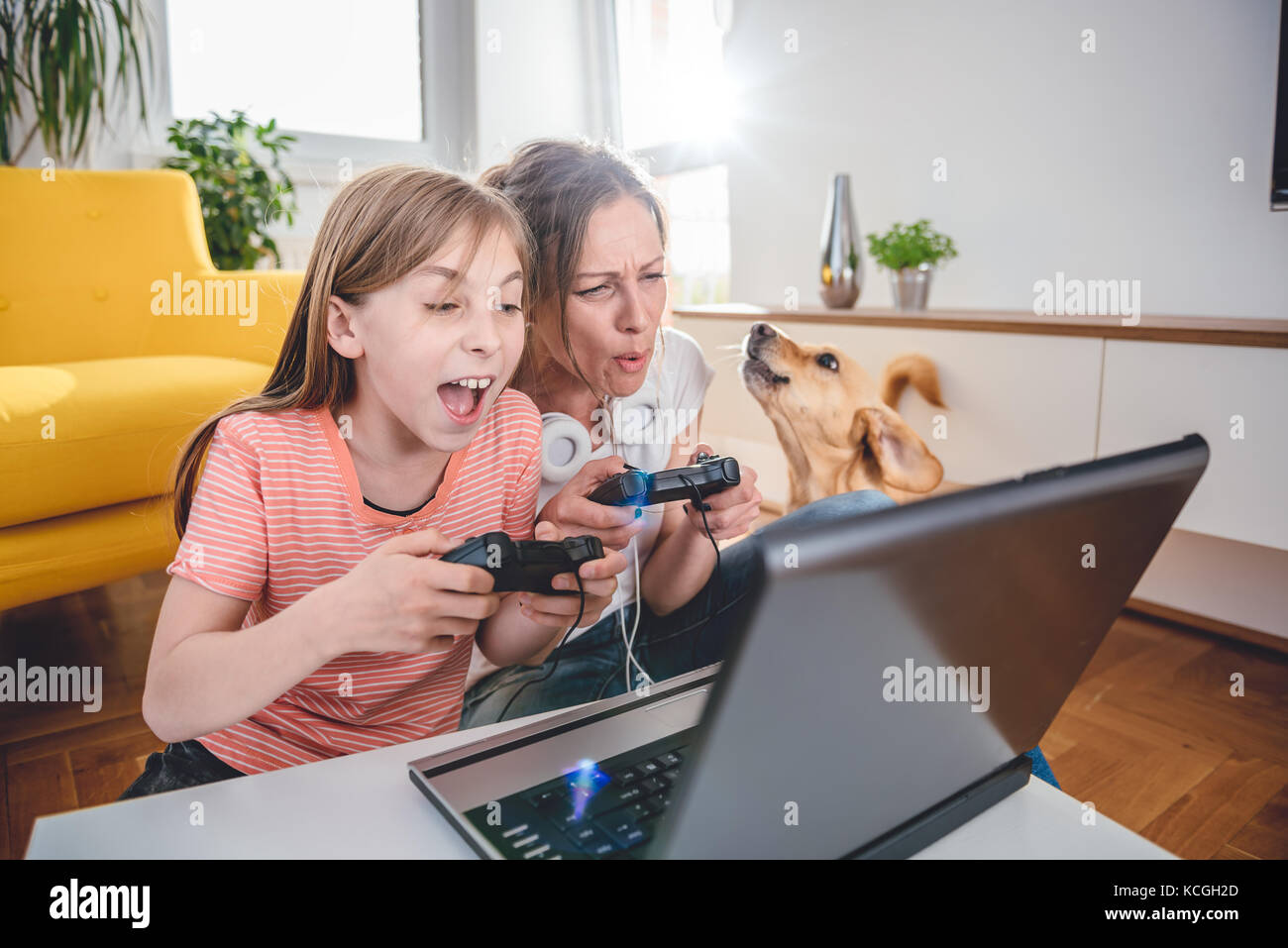 Mother and daughter playing video games on laptop at home Stock Photo ...