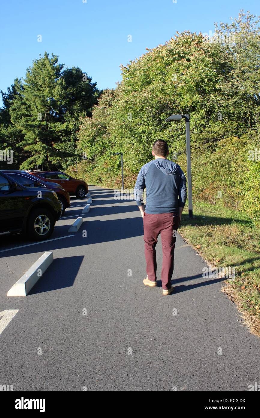 A person walking down a path in a parking lot in the new england area ...