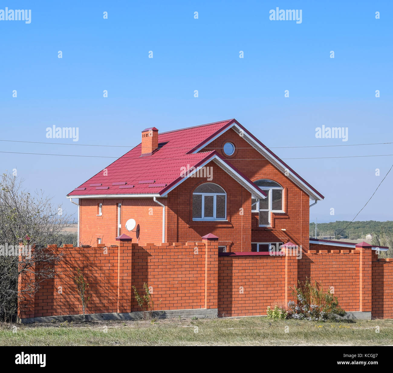 house with a red roof and red brick. Red brick fence. Roof of metal ...