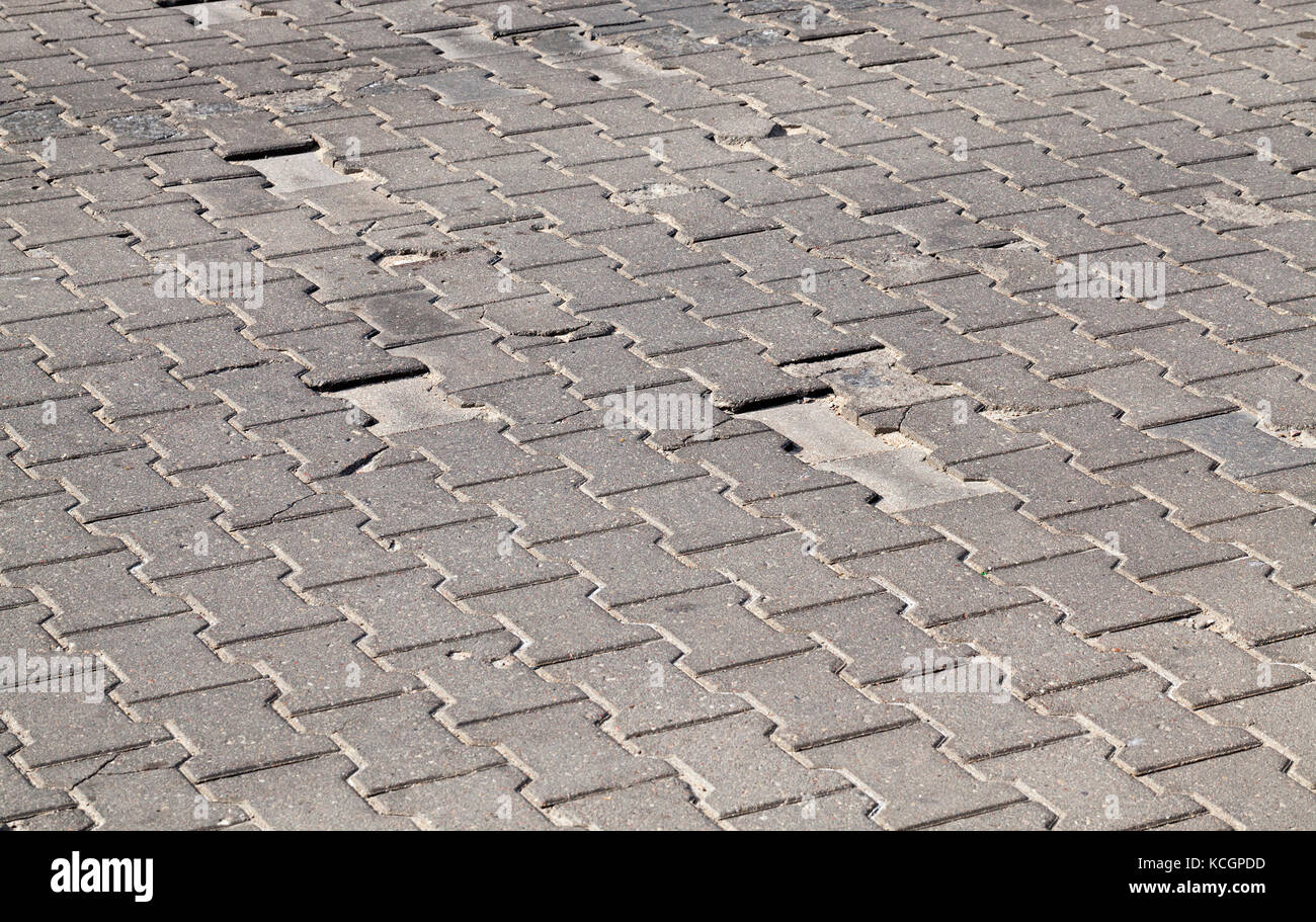 Broken and holey road of gray tiles. Photo close up Stock Photo - Alamy